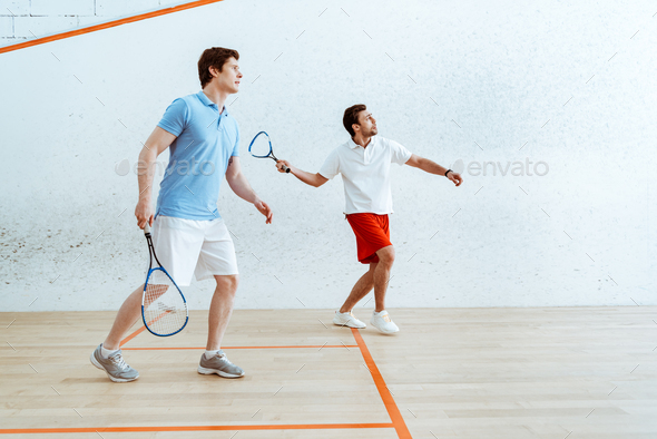 Full length view of two sportsmen playing squash in four-walled court ...