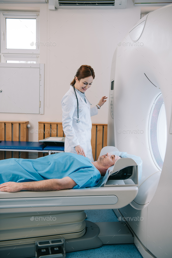 attractive smiling doctor preparing man for scanning in mri machine ...