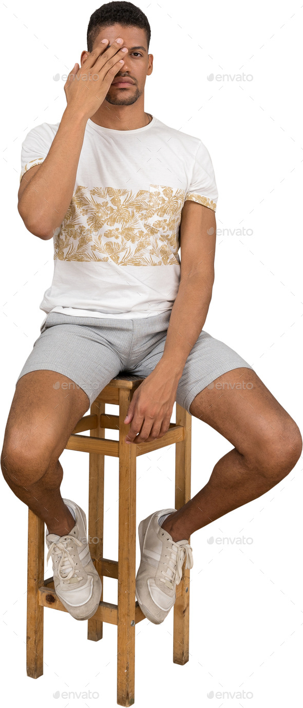 a man sitting on a wooden chair with his hand on his face Stock Photo ...