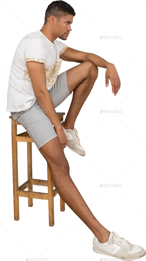 a man sitting on a wooden stool with his legs crossed Stock Photo by Icons8