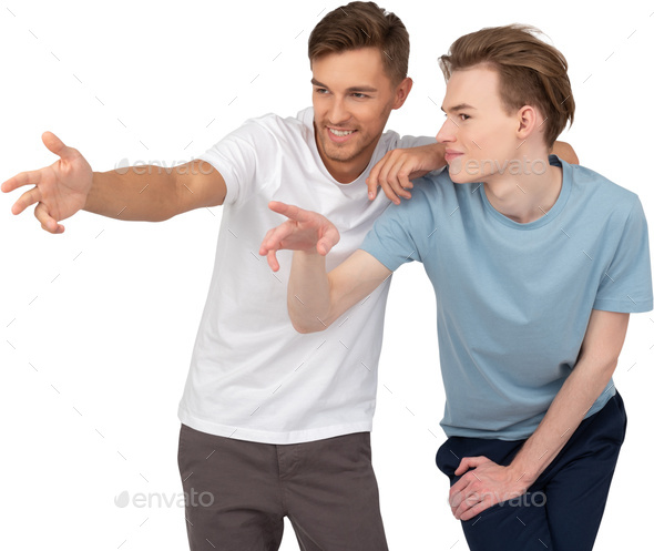 two young men standing next to each other and pointing at something ...
