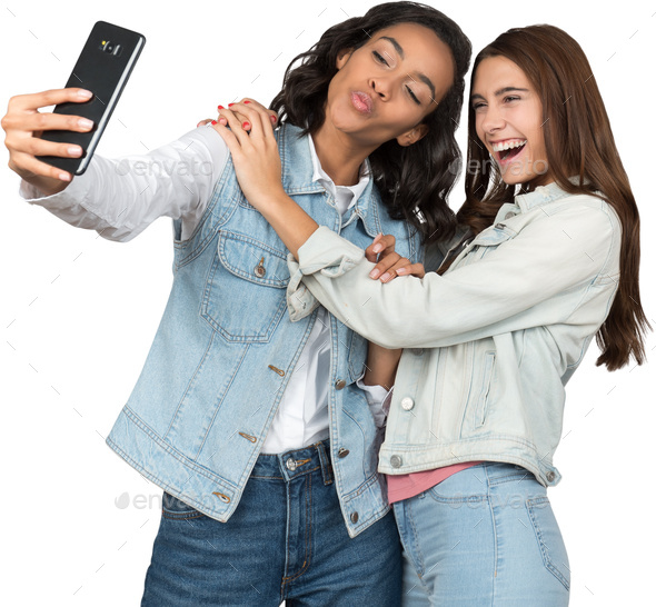 two young women are hugging each other while looking at a cell phone ...