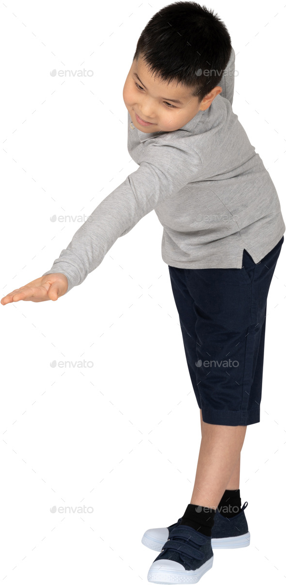 a young boy standing with his arm outstretched and pointing at ...