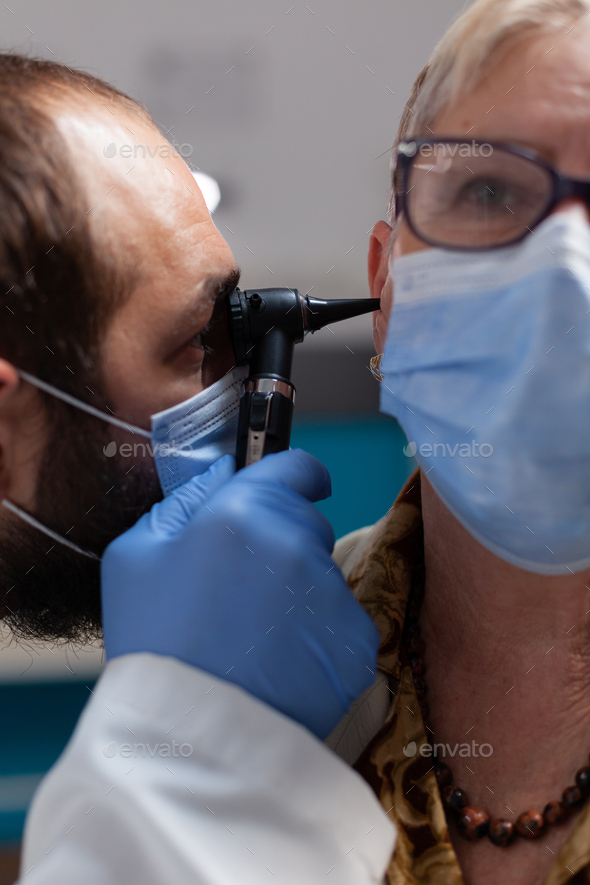 Medic holding otoscope to do ear checkup on elder woman Stock Photo by ...