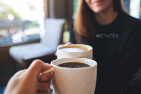 Closeup image of a couple people clinking coffee cups together in cafe ...