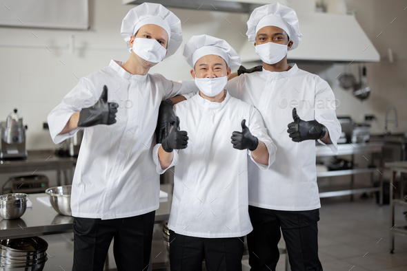 Portrait of multiracial team of three chefs standing together on ...