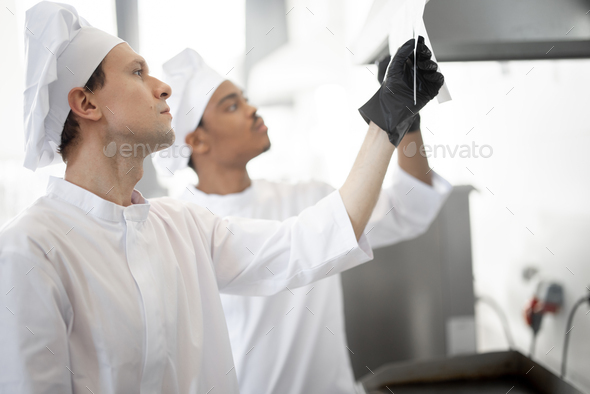 Chefs look on printed checks with orders while cooking in the ...