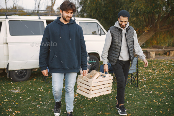Two Caucasian men carrying crate with logs Stock Photo by prostooleh