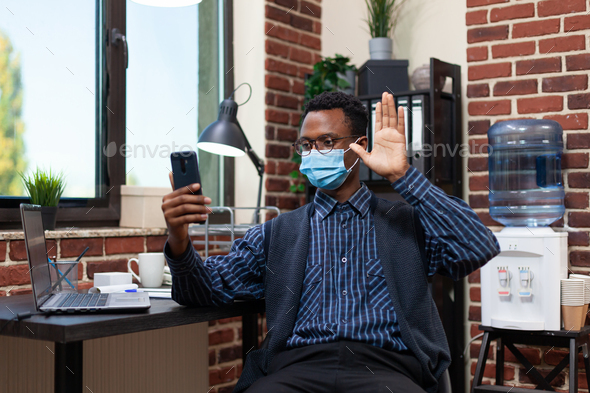 Startup employee wearing covid mask waving hello presenting himself in ...