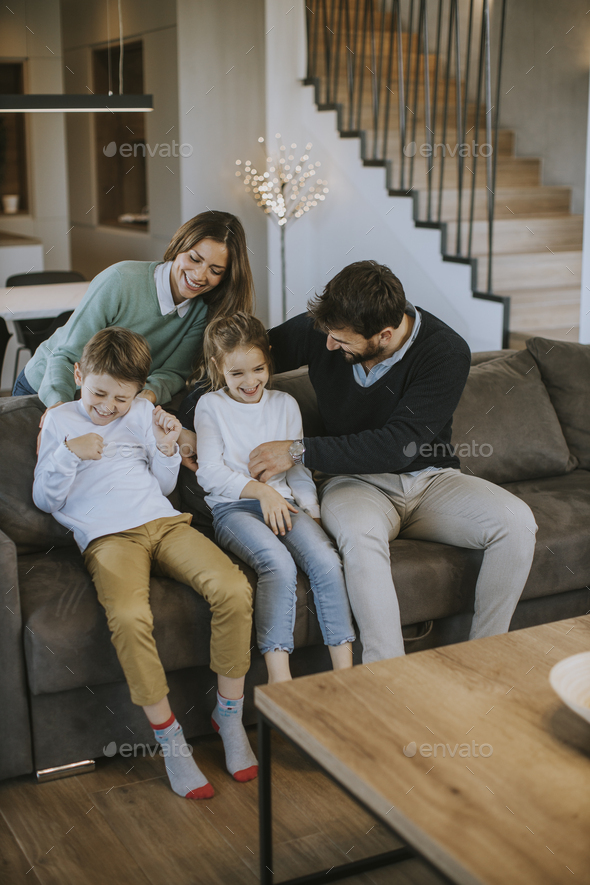Happy family with two kids enjoy time together on couch in living room ...