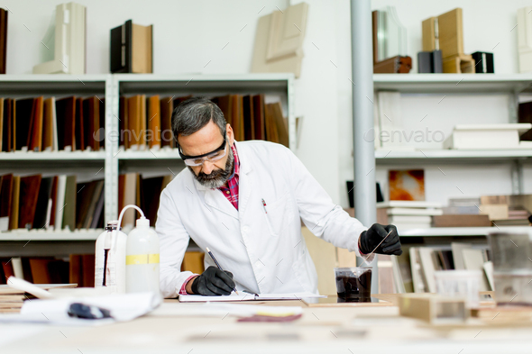 Handsome mature engineer working in laboratory in the furniture factory ...