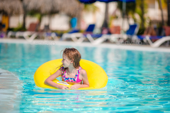 Little girl with inflatable rubber circle in outdoor swimming pool ...