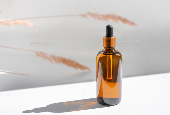 Amber glass bottle with cosmetic body oil on a white background with ...