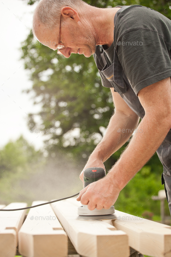 Carpenter sanding a wood with sander outdoors Stock Photo by PaulSchlemmer