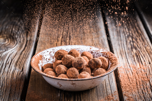 Falling cocoa powder on sweet chocolate balls Stock Photo by Shaiith