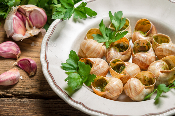 Closeup of snails baked in garlic butter and served with parsley Stock ...