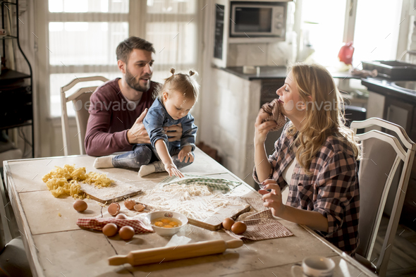 Happy family making pasta in the kitchen at home Stock Photo by BGStock72