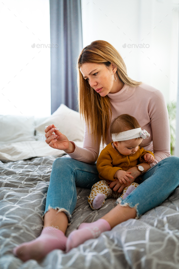 Mother measuring temperature of her ill kid. Sick child with high fever, mother holding ...