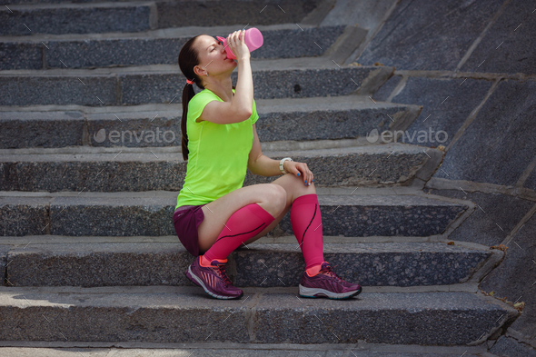 trainer rest and drink water standing on the stairs after a joint ...