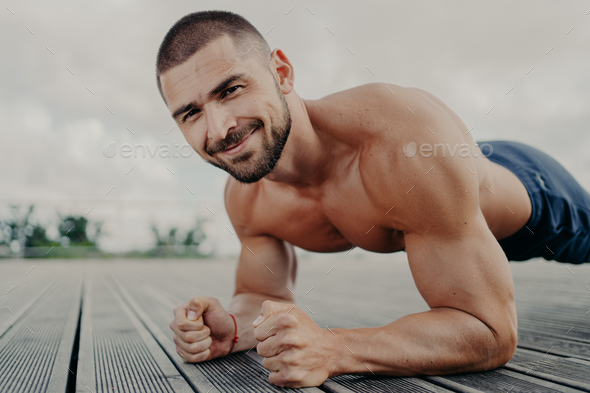Sportsman stands in plank and goes in for sport outdoor, has regular ...