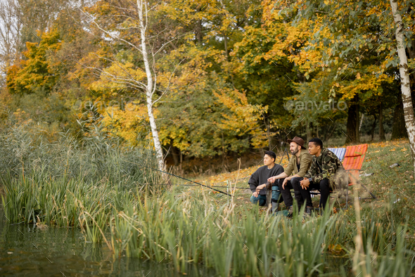 Multiracial male friends fishing together Stock Photo by RossHelen