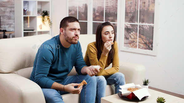 Concentrated young couple eating fried chicken Stock Photo by DC_Studio