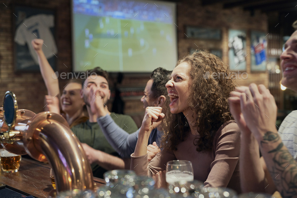 Cheering friends of soccer fans in the pub Stock Photo by gpointstudio