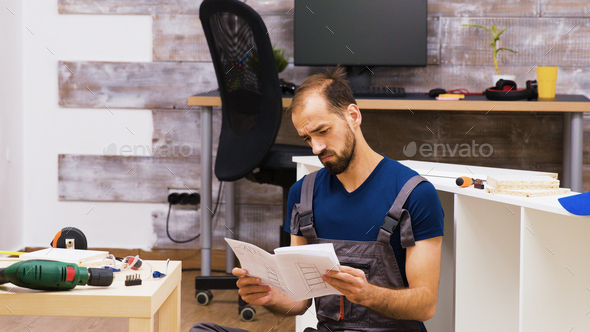 Concentrated worker reading assembly instruction Stock Photo by DC_Studio