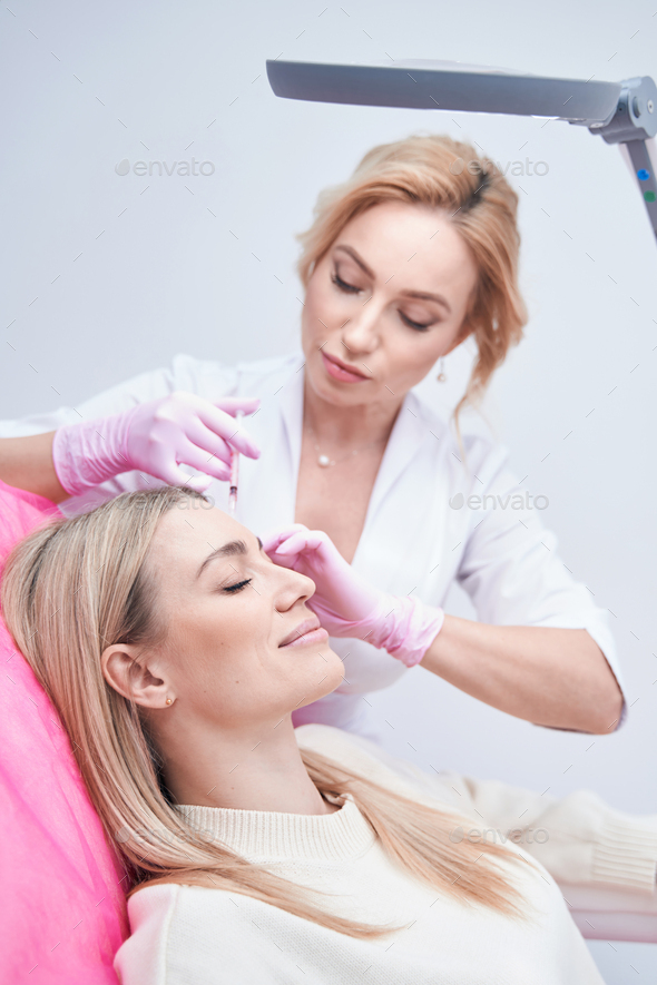 Concentrated dermatologist administering subcutaneous injection to ...