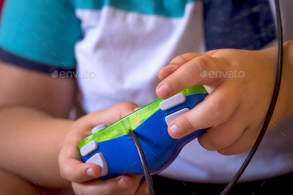 Child's hands playing with a console controller. Stock Photo by armacuatro