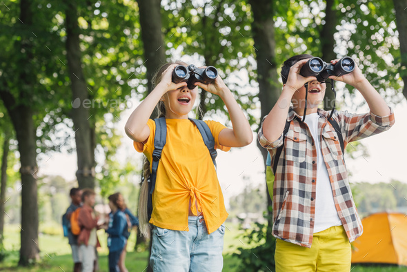 selective focus of happy kids looking through binoculars Stock Photo by LightFieldStudios