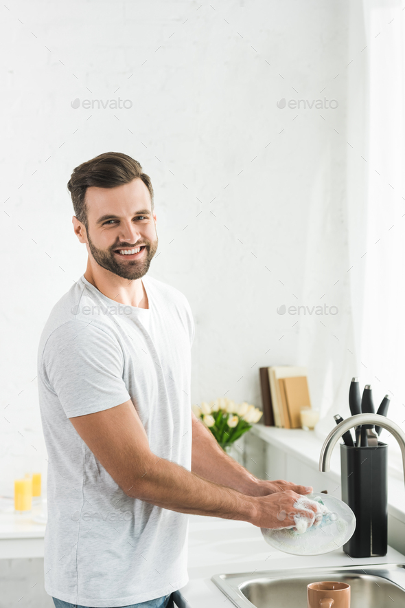 handsome smiling man washing dishes at kitchen in morning Stock Photo ...