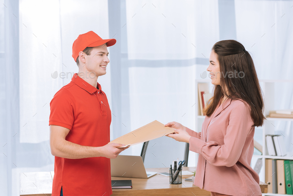 Side view of delivery man giving envelope to smiling businesswoman in ...