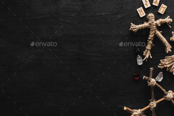 top view of voodoo doll, ancient runes, crystals and pentagram on black ...