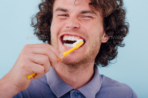 close up. teeth cleaning, young man wash on teeth with brush and paste ...