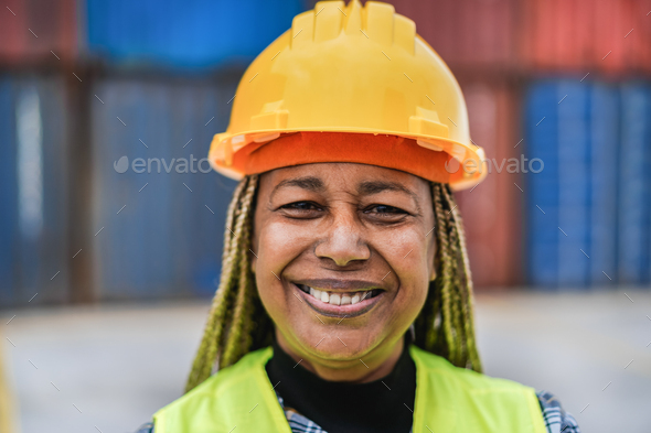 Worker African senior woman smiling on camera with industrial port on ...