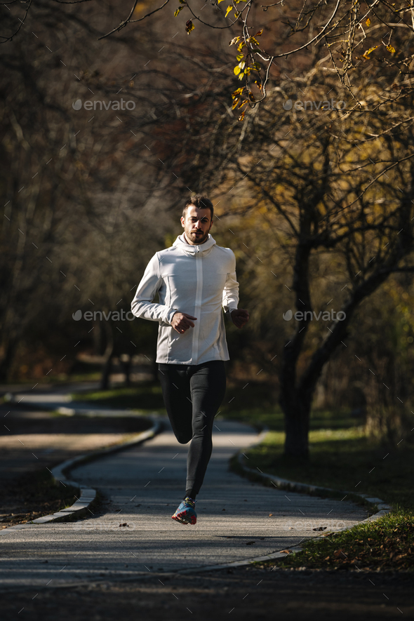 Young man running at park during autumn morning Stock Photo by carlesiturbe