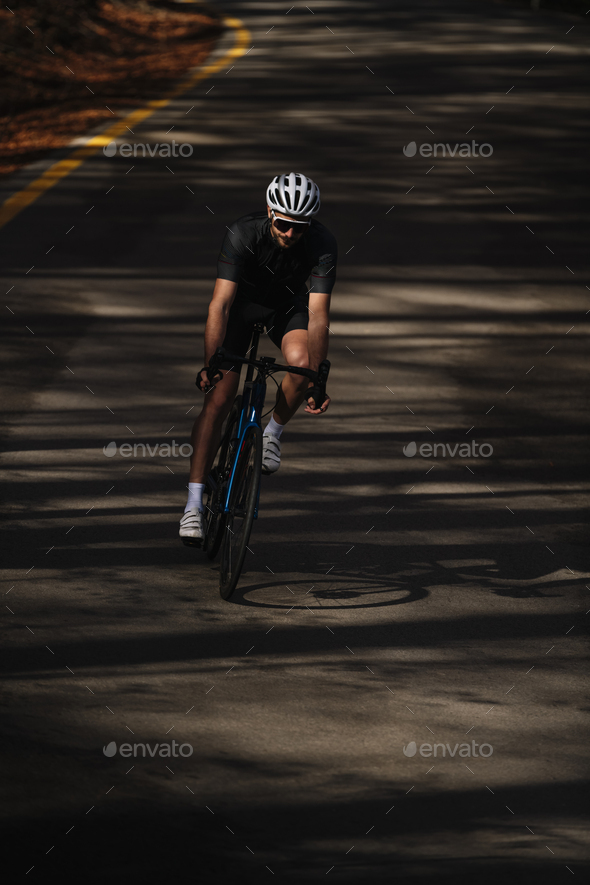 Cyclist riding a bike on a curved road in autumn scenery Stock Photo by ...