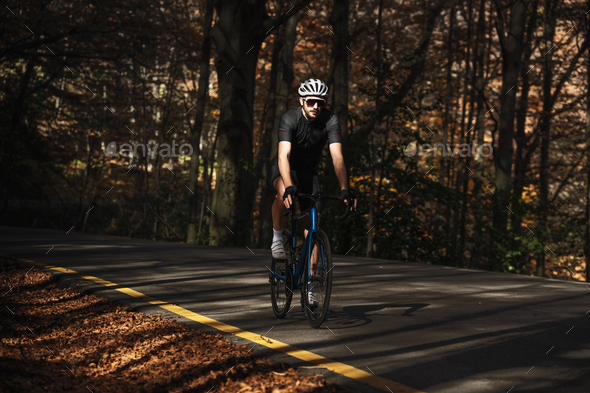 Cyclist riding a bike on a curved road in autumn scenery Stock Photo by ...
