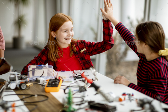 Cute little girls programming electric toys and robots at robotics ...