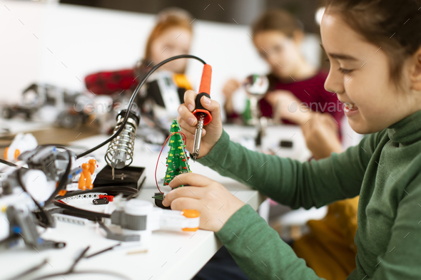 Happy kids programming electric toys and robots at robotics classroom ...