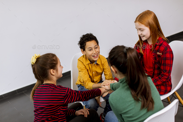 Portrait of cute little kids in jeans talking and sitting in chairs ...