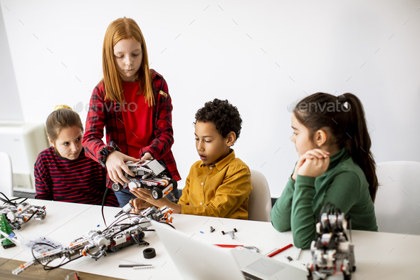 Happy kids programming electric toys and robots at robotics classroom ...
