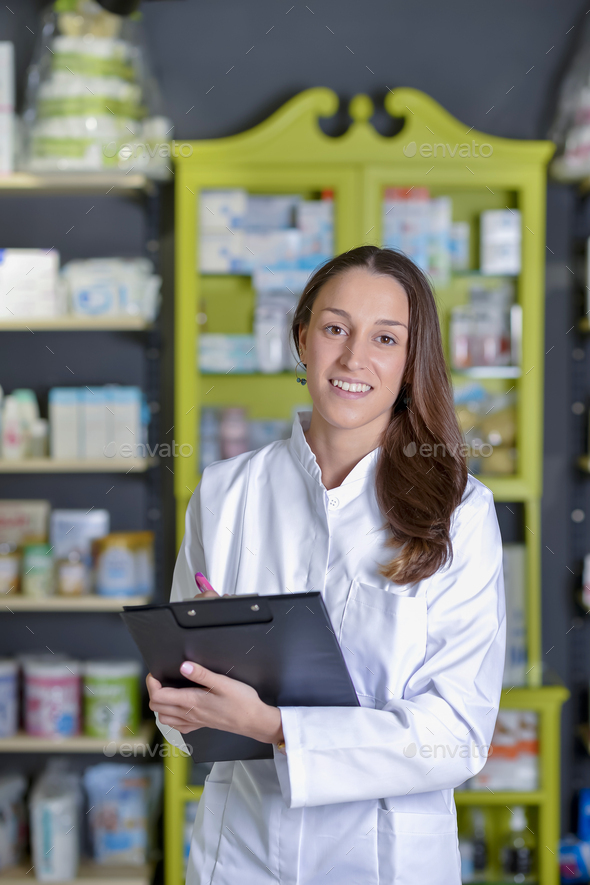 Beautiful pharmacist using notepad at the pharmacy Stock Photo by ...
