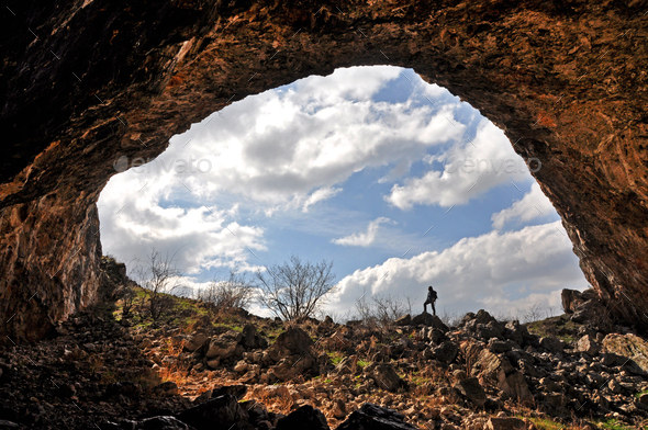 Inside view of a cave entrance with a cave explorer Stock Photo by salajean