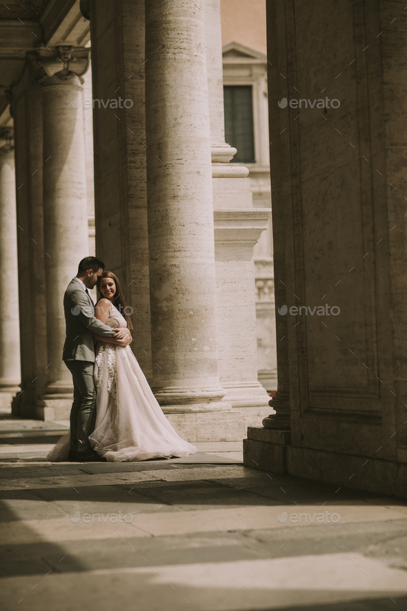 Young newly married couple posing in Rome with beautiful and ancient ...