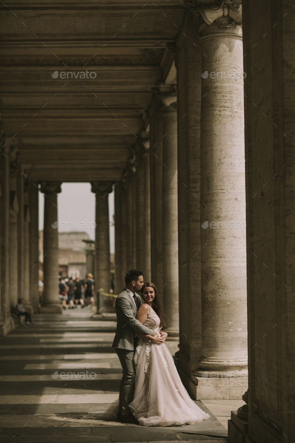 Young newly married couple posing in Rome with beautiful and ancient ...
