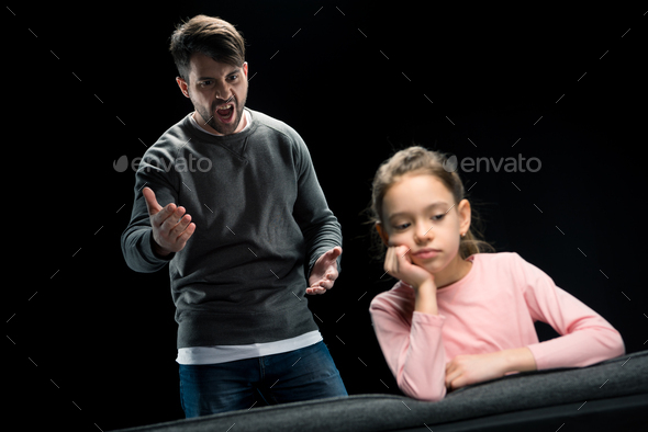 Aggressive father screaming at upset little daughter isolated on black ...