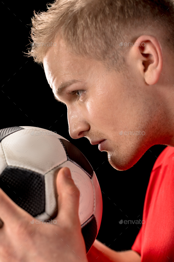 Side view of concentrated soccer player holding ball Stock Photo by ...