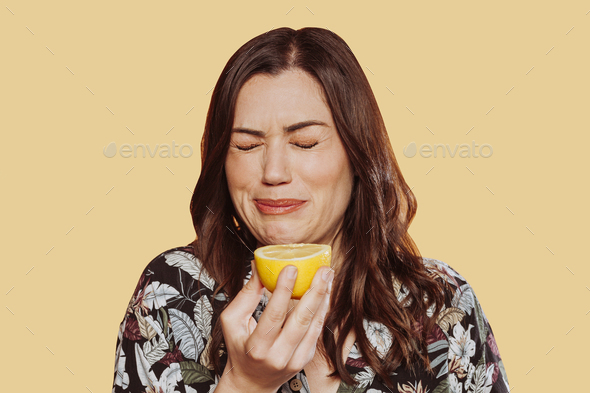 Woman eating lemon doing funny face expression Stock Photo by carlesmiro